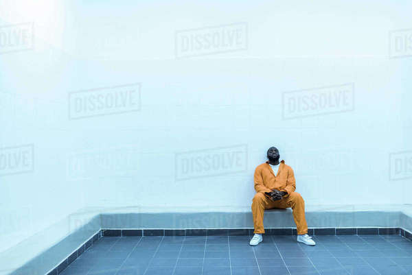 African American prisoner sitting on bench in prison cell - Royalty ...