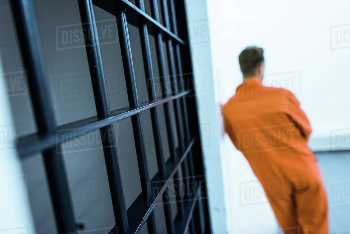 Rear view of prisoner leaning on wall in prison cell - Royalty-free ...