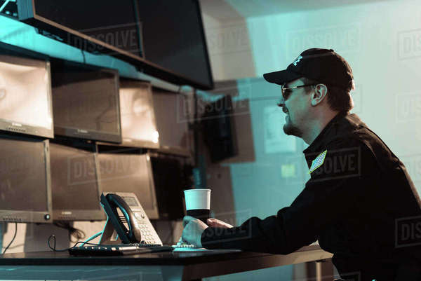side view of smiling prison guard sitting with cup of coffee and ...