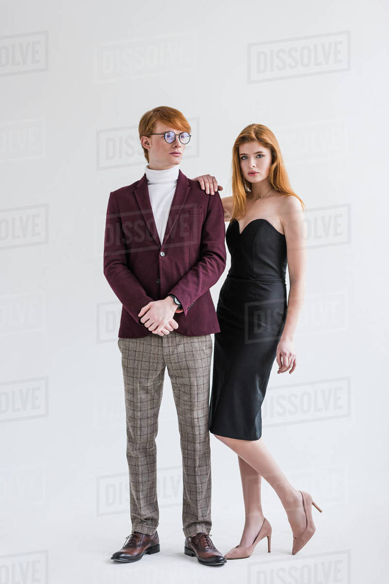 Young couple of fashion models dressed in formal wear isolated on grey ...