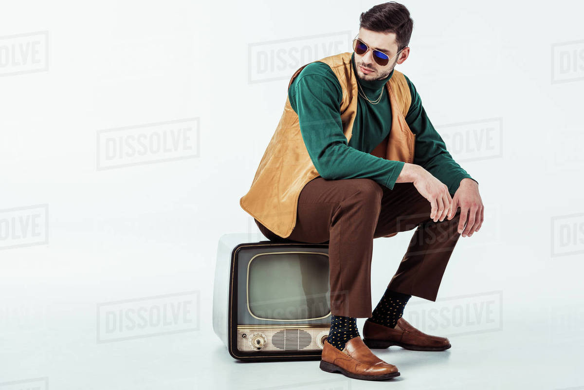 Handsome retro styled man sitting on vintage television on white ...