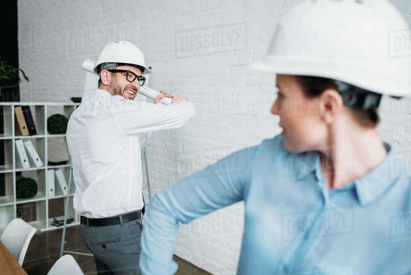 Architects fighting with rolled building plans at office - Royalty-free ...