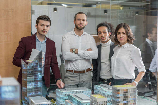 Group of architects standing next to building models at office ...