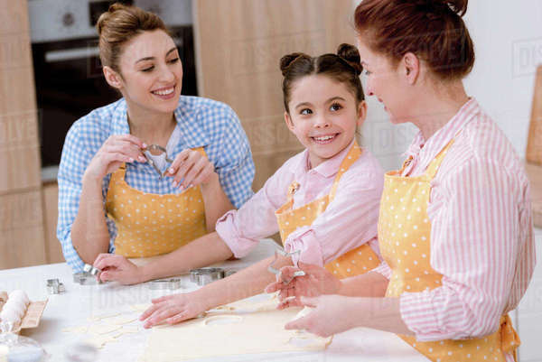 Three generations of beautiful women cooking together at kitchen ...
