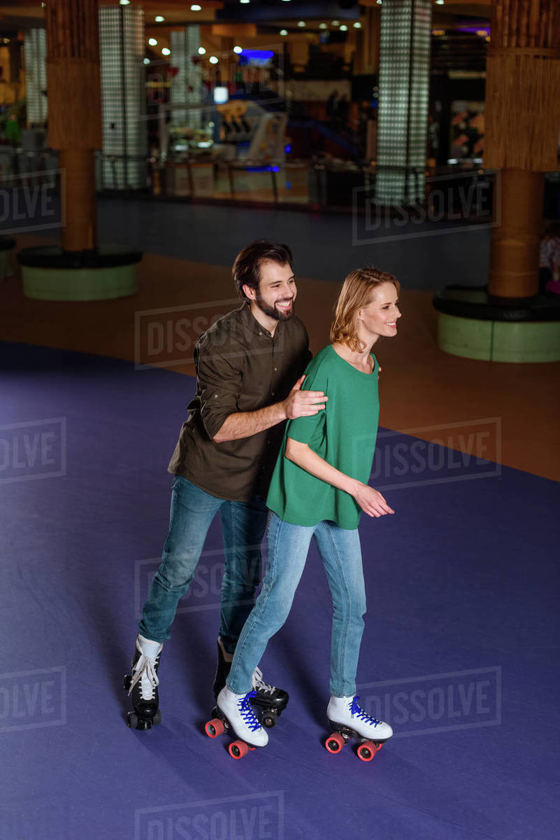 Young smiling couple skating together on roller rink - Royalty-free ...