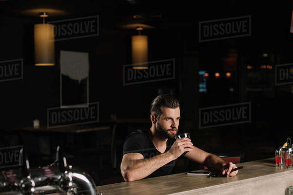 Handsome man sitting at bar counter and drinking whiskey - Royalty-free ...