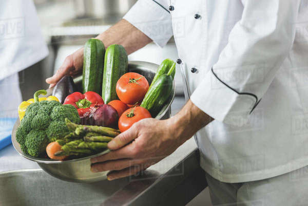 Cropped image of chef holding bowl with vegetables at restaurant ...