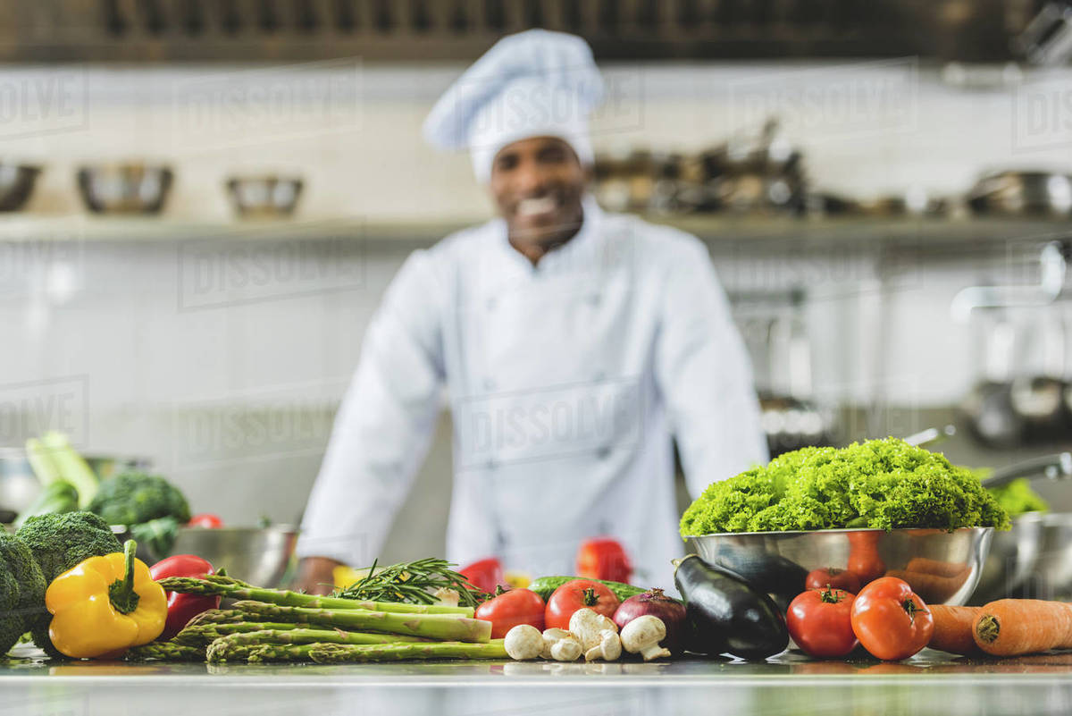 Smiling African American chef at restaurant kitchen with vegetables on ...