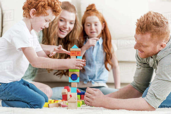 beautiful redhead family playing with constructor on floor at home ...