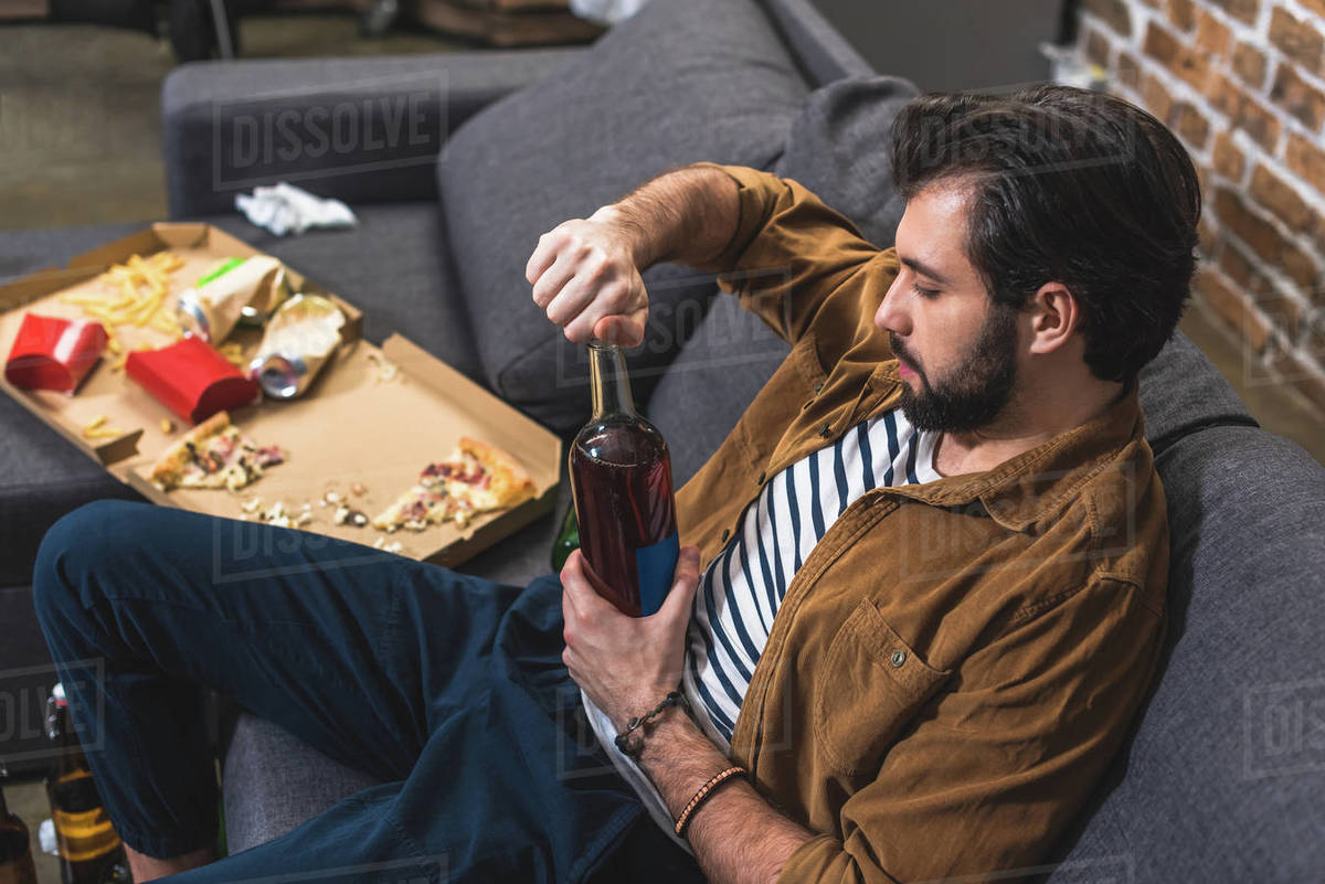 Side view of loner opening bottle of alcohol drink at living room ...