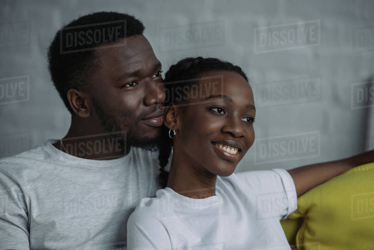 Happy young african american couple looking away together at home ...