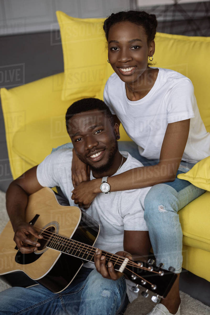 Happy young african american couple with acoustic guitar smiling at ...