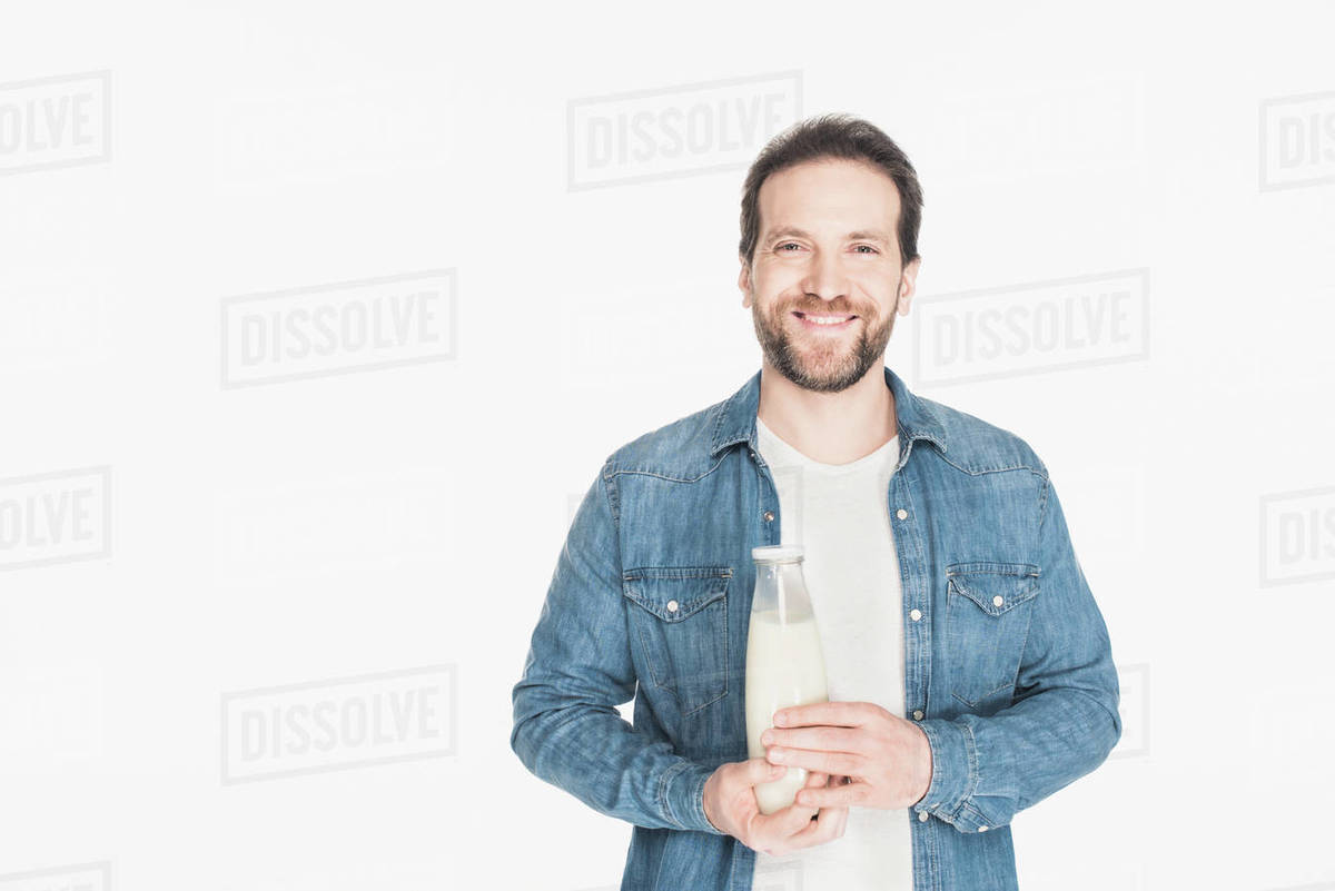 Portrait of smiling man with glass bottle of milk in hands looking at ...