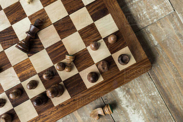 Top view of chess board with scattered black chess pieces on rusitc ...