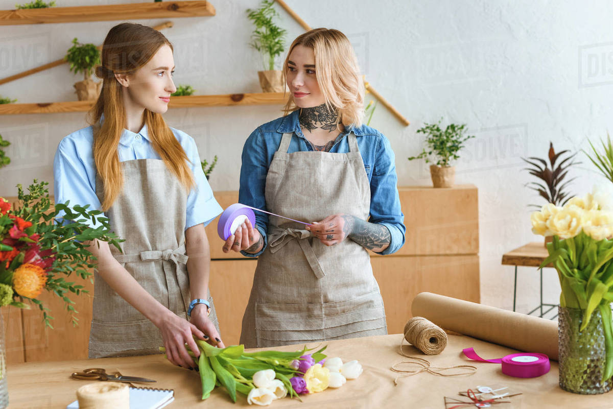 beautiful young florists working together and smiling each other in ...