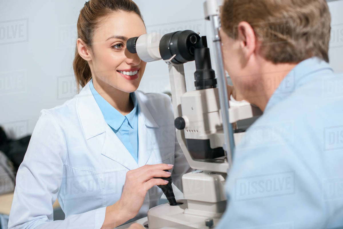 Professional optician examining man with modern optical equipment - Royalty-free Stock Photo ...