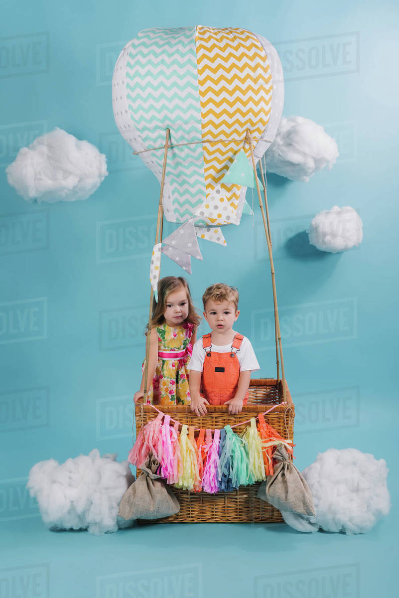 Adorable little kids pretending to fly on hot air balloon in cloudy sky ...