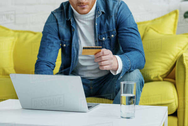 Young man holding credit card while using laptop - Royalty-free Stock ...