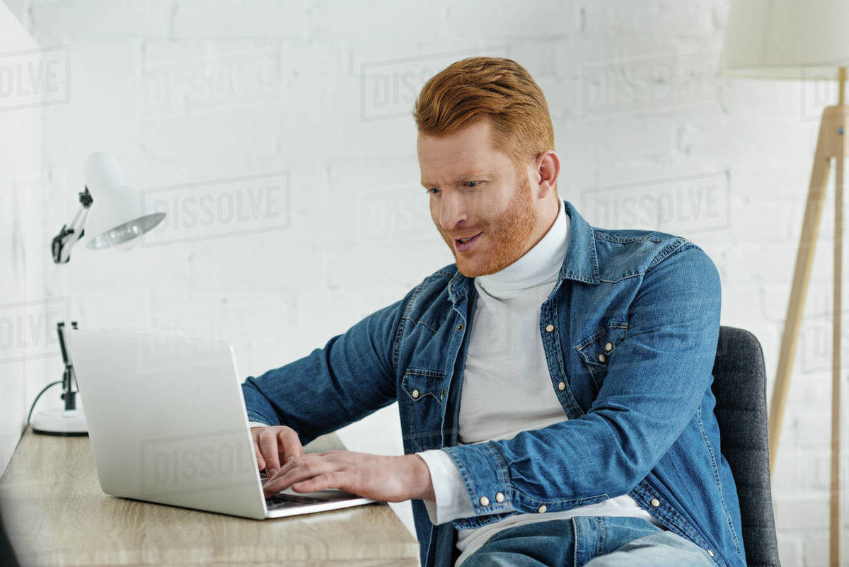 Young professional man looking at laptop screen - Stock Photo - Dissolve