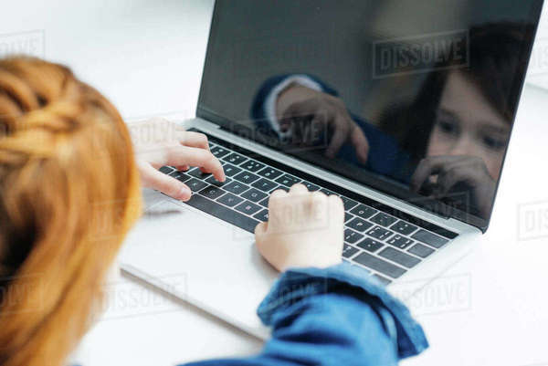 Laptop screen with reflection of cute child - Stock Photo - Dissolve