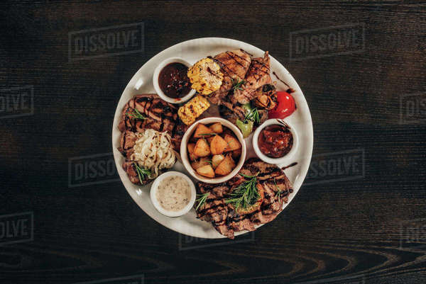 Top view of plate with beef steaks, chicken wings and grilled ...