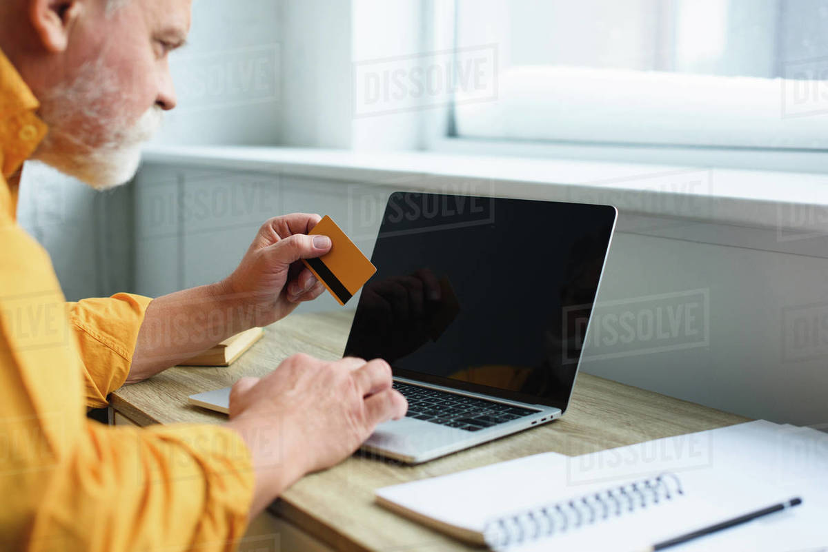 Cropped shot of man holding credit card and using laptop with blank ...