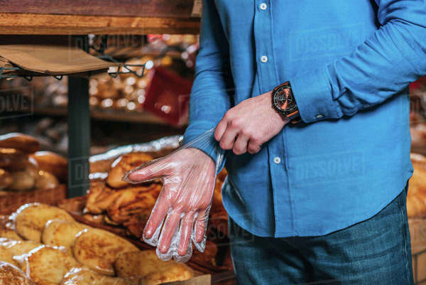 Cropped shot of man wearing disposable glove in grocery shop - Royalty ...