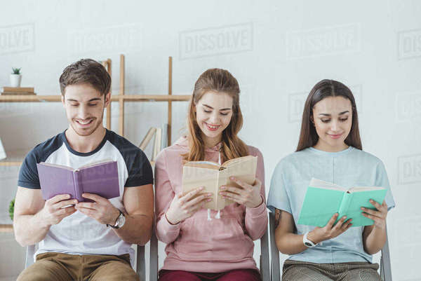 Young multiethnic students sitting and reading books together - Royalty ...