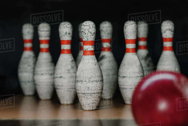 Close-up shot of grungy bowling pins with red ball on foreground ...