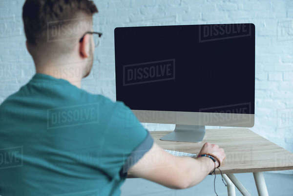 Rear view of man looking at computer screen on table - Royalty-free ...