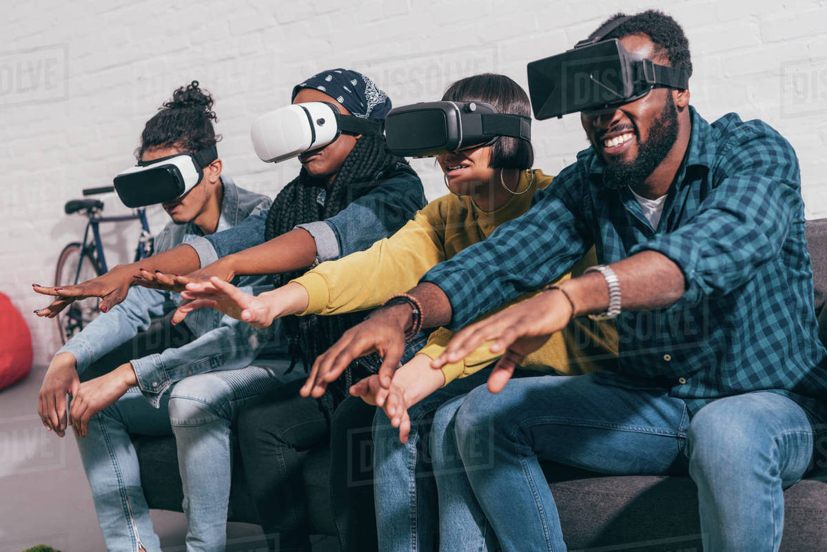 Group of young multicultural friends using virtual reality headsets ...