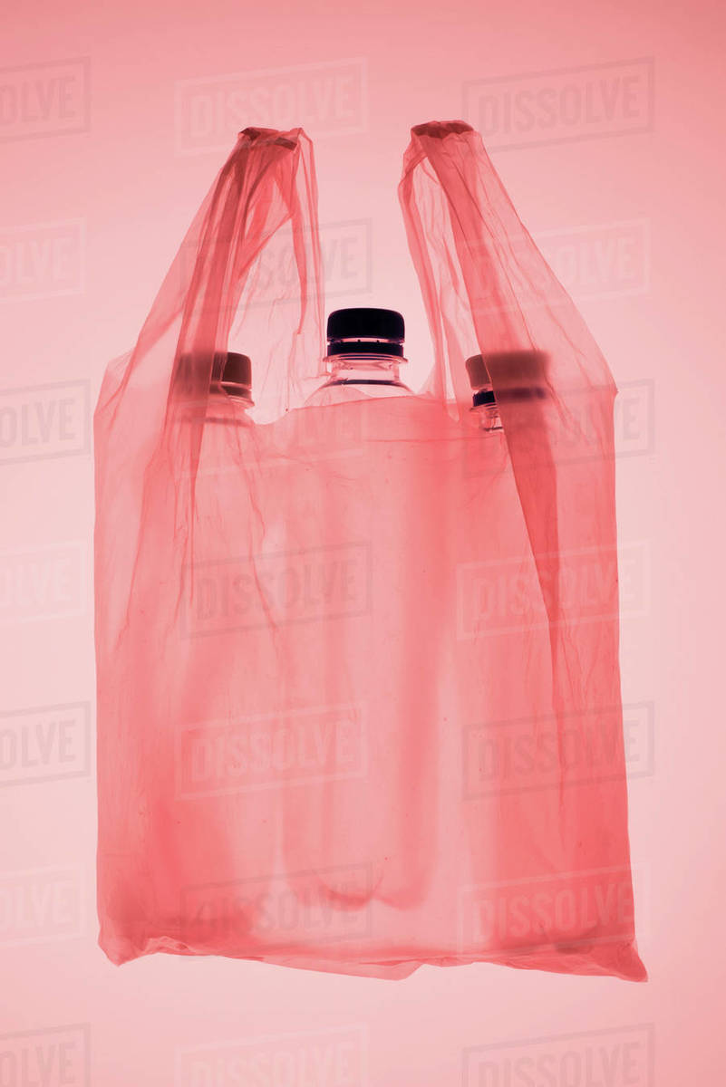 Transparent plastic bag with plastic bottles under pastel pink toned ...