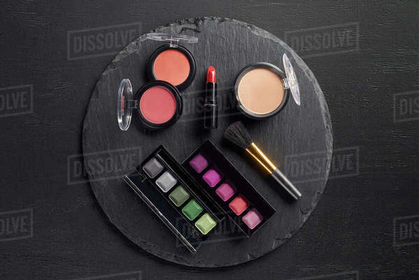 Make up set with eye shadows and lipstick on round slate background ...