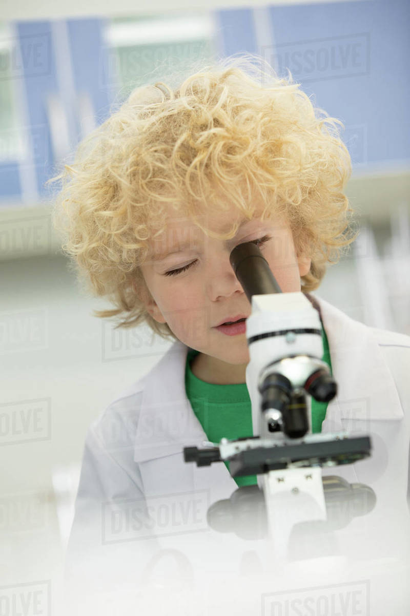 Little boy in lab coat looking through microscope - Stock Photo - Dissolve