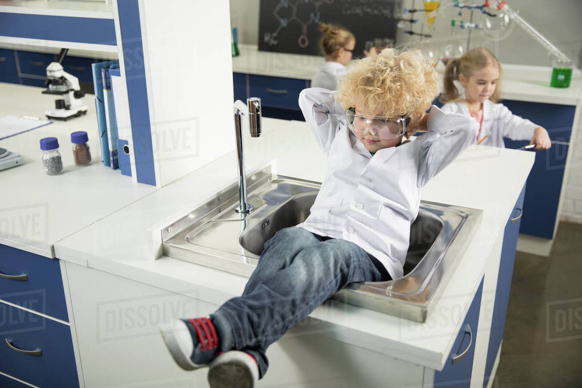 Relaxed little boy sitting in sink in science laboratory - Royalty-free ...