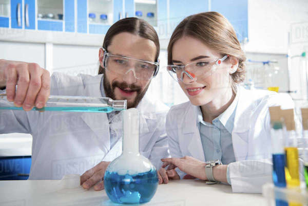 Young male and female scientists making experiment in laboratory ...