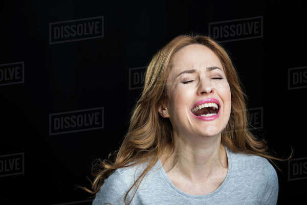 Young beautiful woman screaming in exasperate isolated on black ...