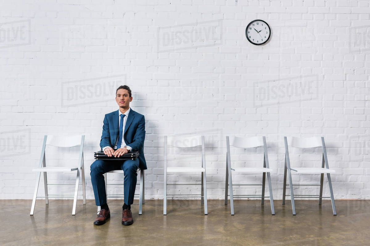 Businessman with briefcase sitting on chair and waiting - Royalty-free ...