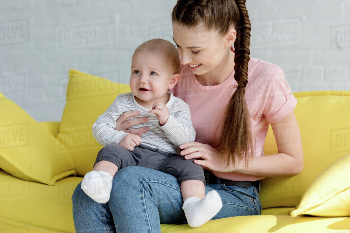 Young mother sitting on sofa with little baby - Royalty-free Stock ...