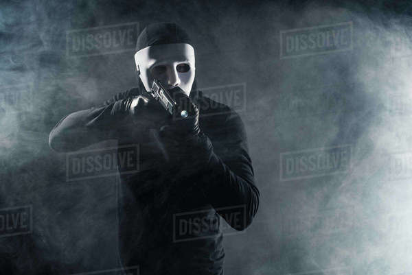 Man in mask and balaclava aiming with gun and flashlight - Stock Photo ...