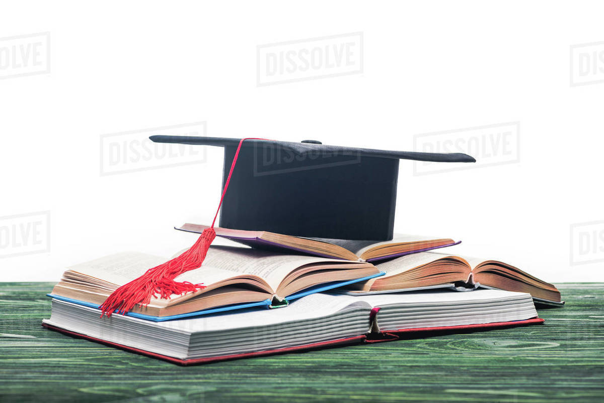 Open books with graduation cap on top - Royalty-free Stock Photo | Dissolve