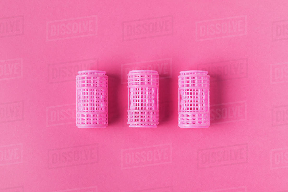 Top view of pink curlers on pink background - Stock Photo - Dissolve
