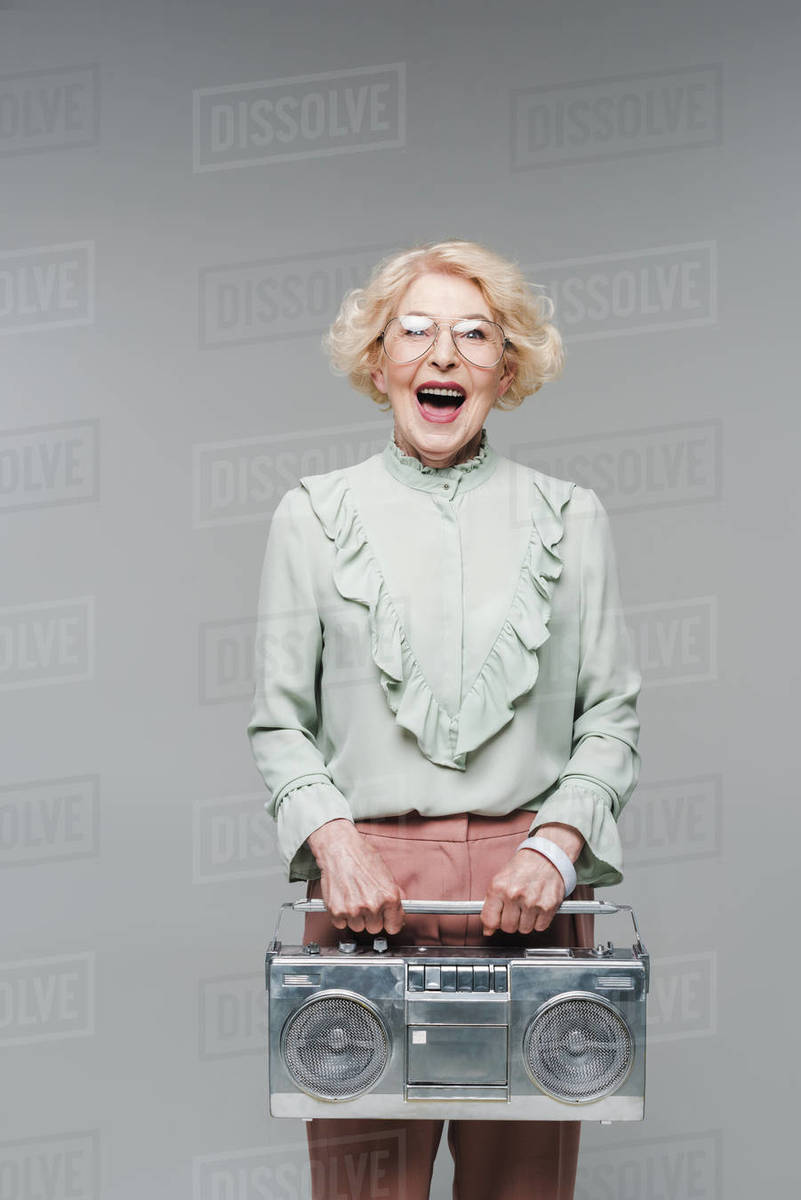 Shouting senior woman with vintage boombox isolated on grey - Royalty ...