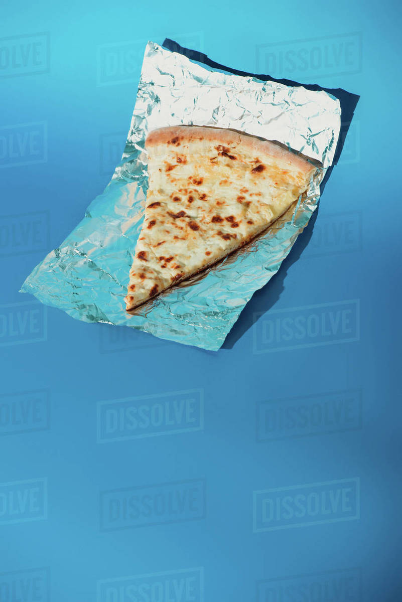 Close up view of piece of Italian pizza on foil on blue background ...