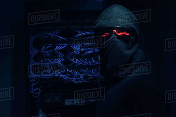 Obscured view of hacker in eyeglasses and mask looking at camera with ...