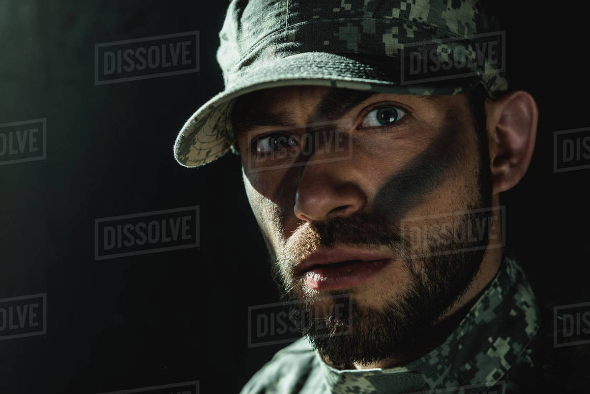 close-up portrait of soldier with camouflage on face looking at camera ...