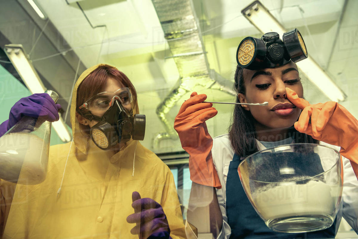 low angle view of woman sniffing drugs with friend holding flask near y ...
