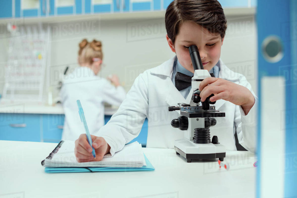 Schoolboy with microscope and copybook in science laboratory, science ...