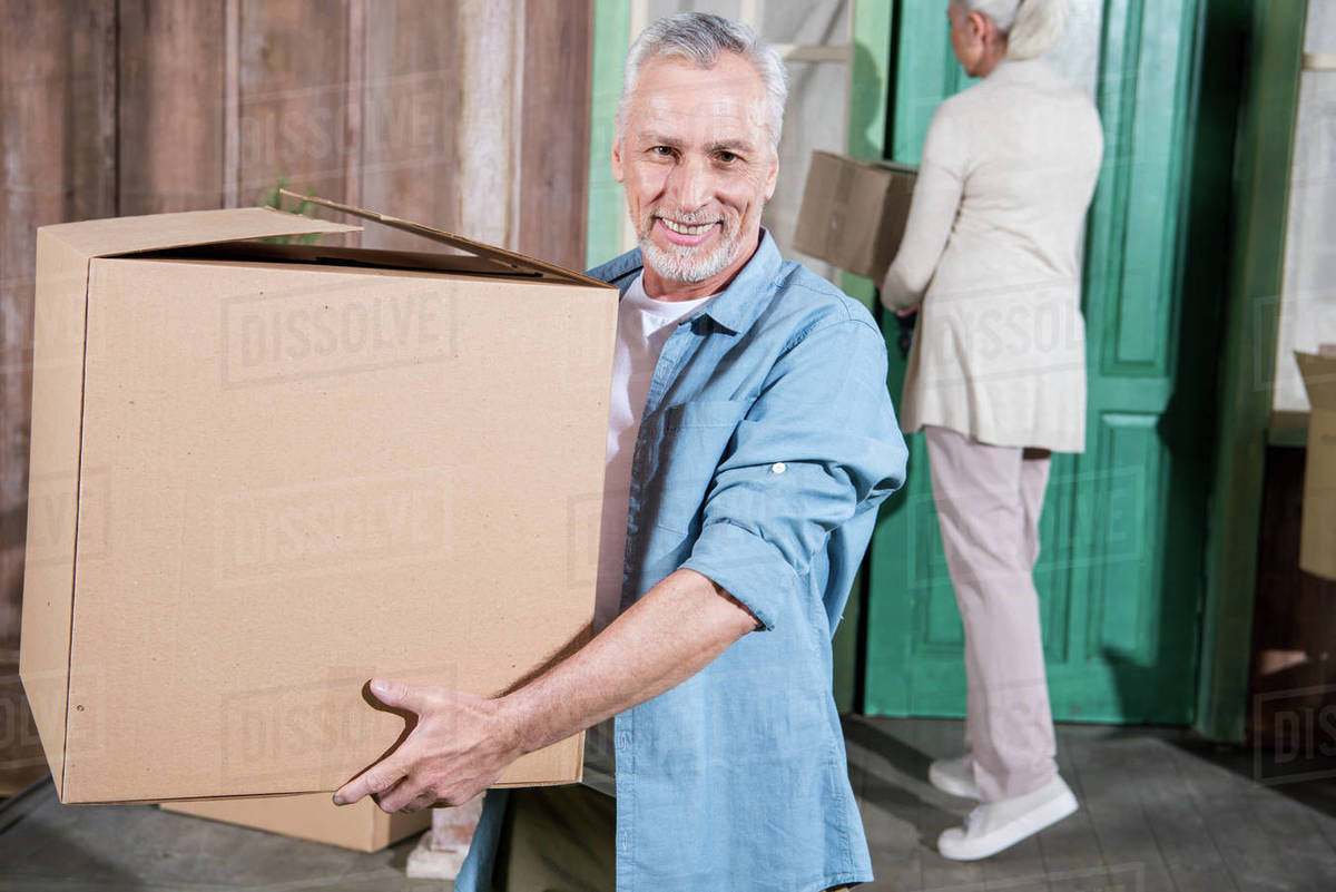 Happy senior man holding cardboard box and smiling at camera - Royalty ...