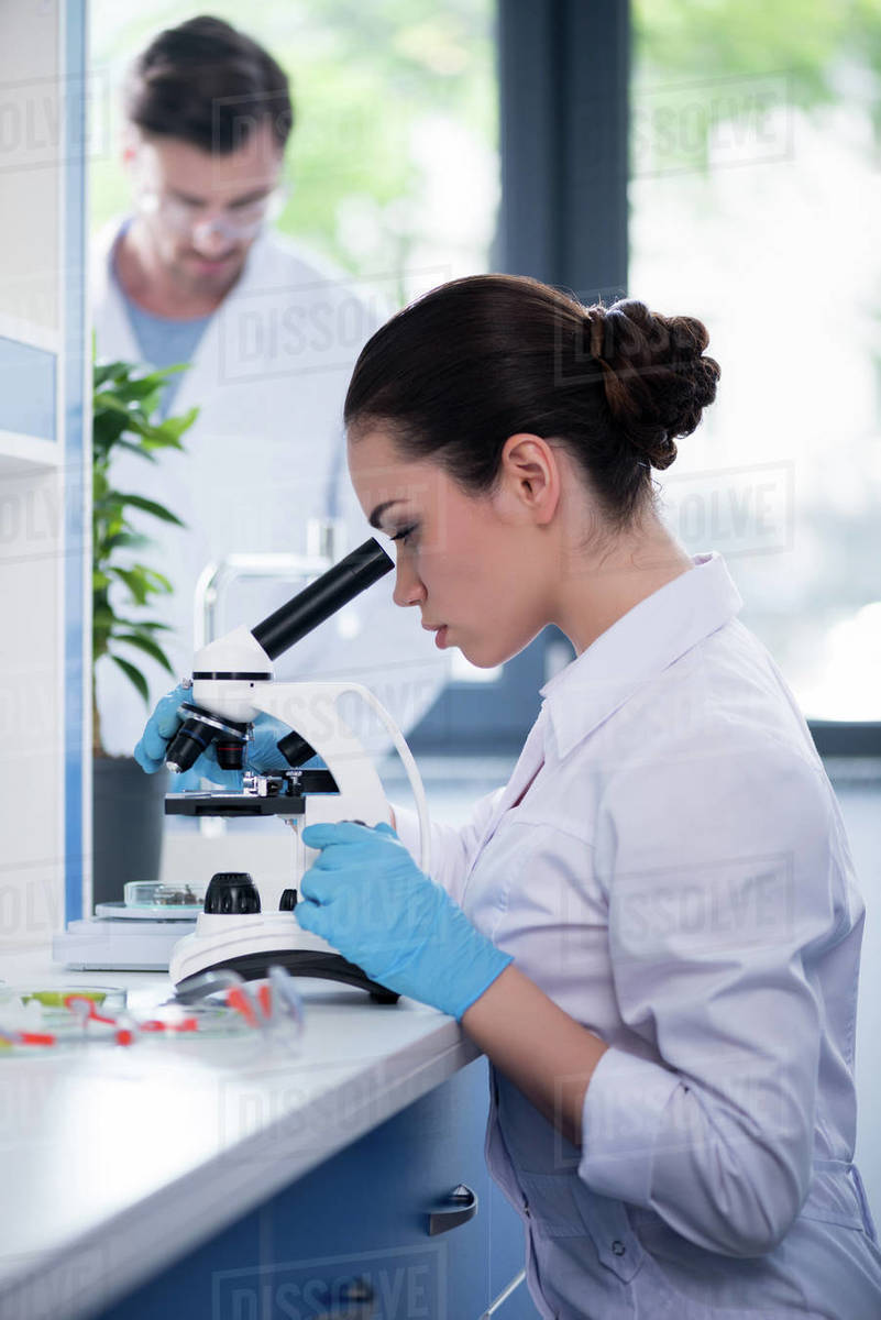 Female scientist during work with microscope at modern biological ...